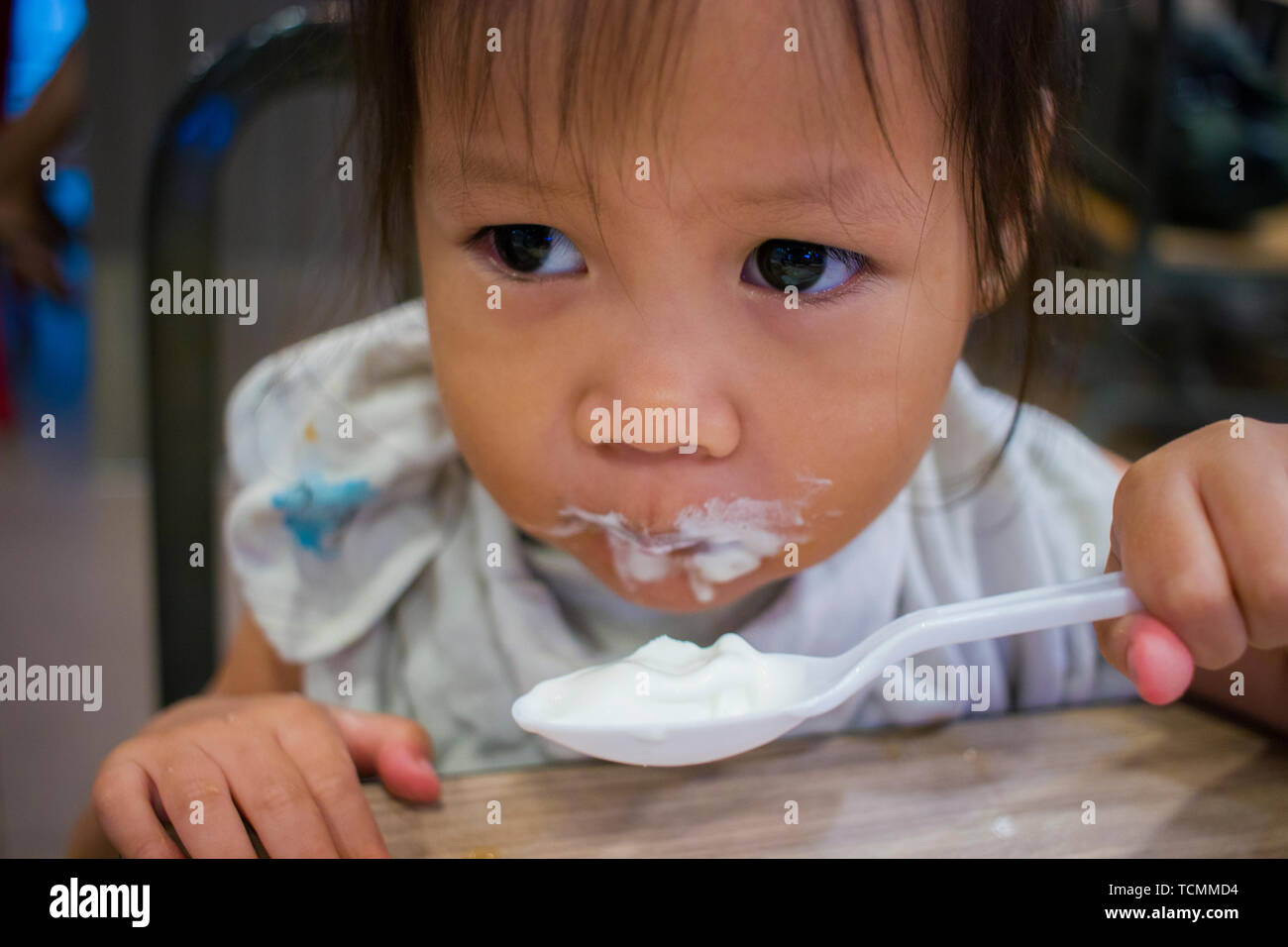The child in the kitchen with a spoon eats ice scream High resolution ...