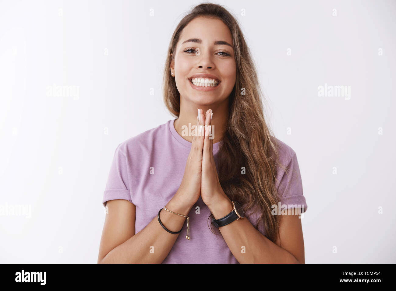 Clingy female friend asking favour smiling broadly holding hands pray ...