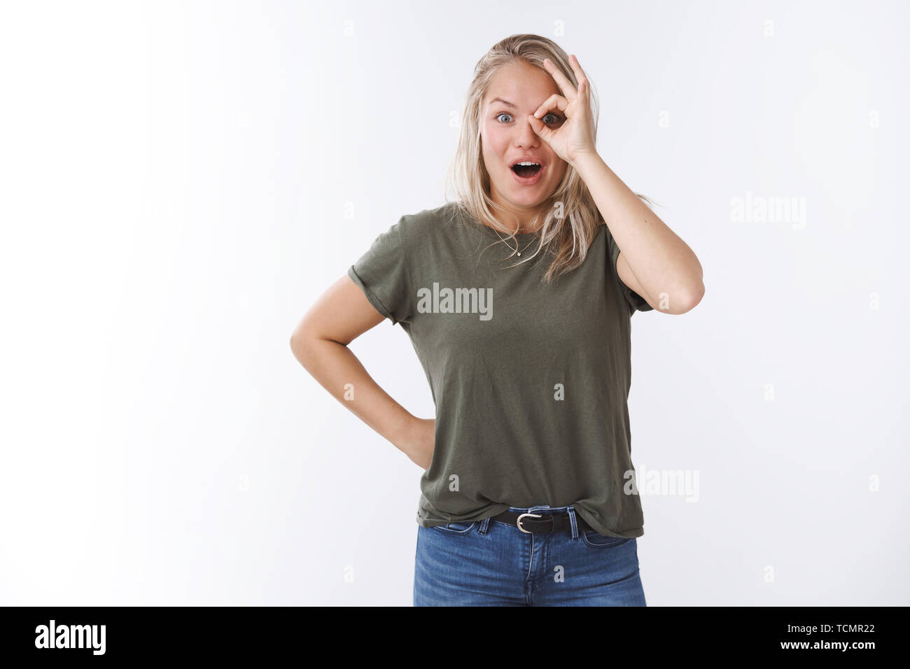 Surprised and amused beautiful caucasian blond in t-shirt showing okay ...