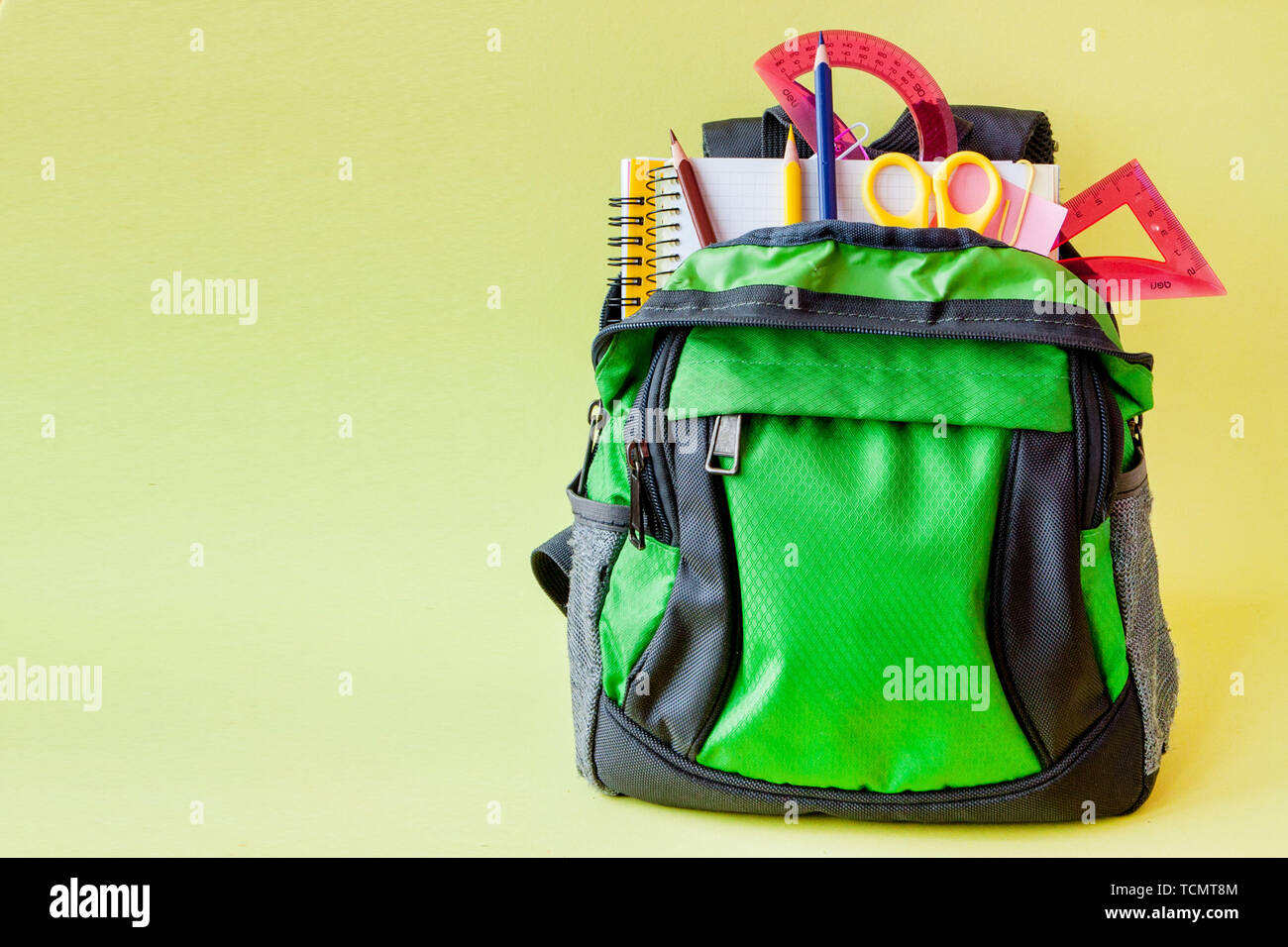 Composition with backpack and school stationery on yellow background ...