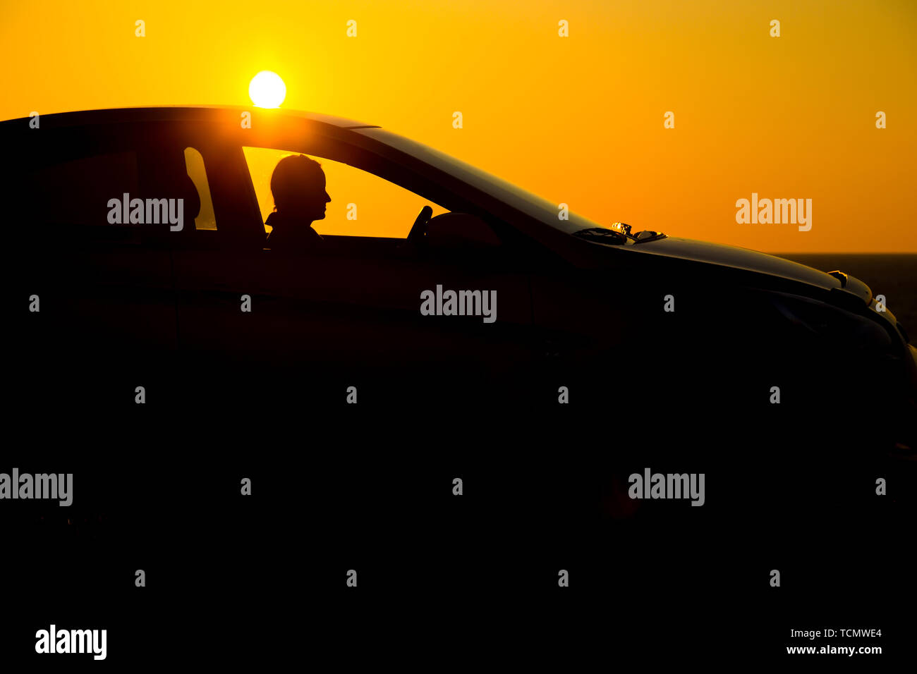 Silhouette of sedan car with girl on the background of beautiful sunset ...