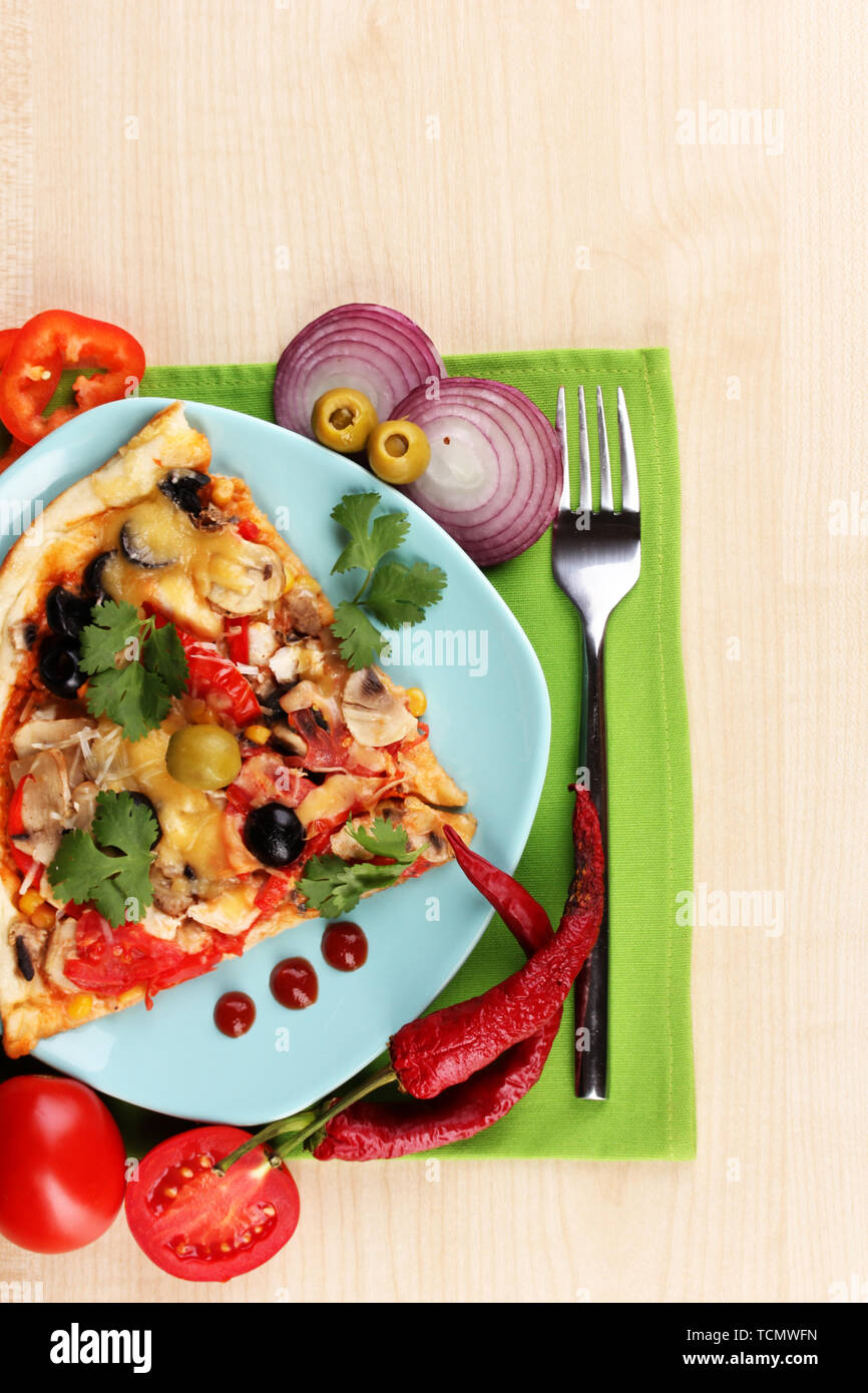 Delicious slice of pizza on color plate with ingredients around close ...