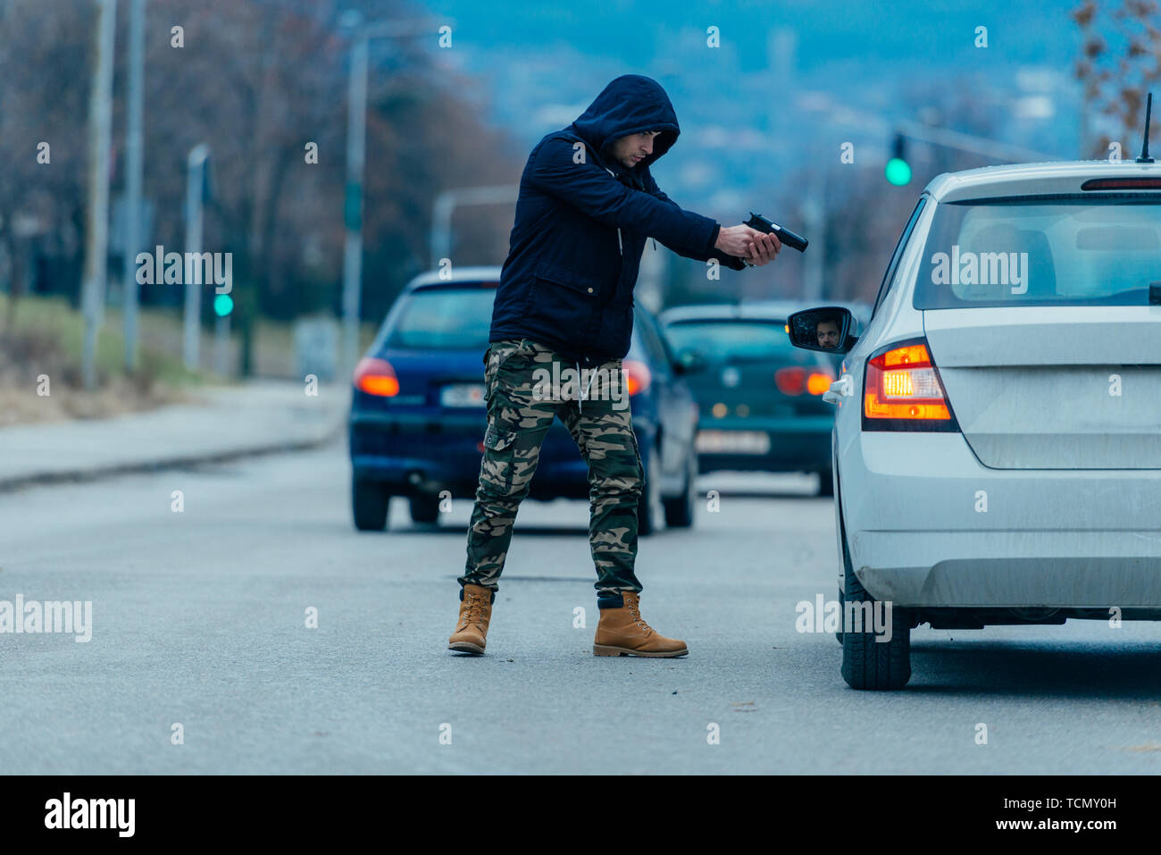 The car thief is pulling the car owner out of his car and trying to get ...