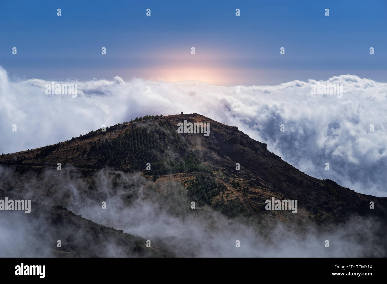 Amazing scene of mountain peak and dense clouds against sky and orange ...