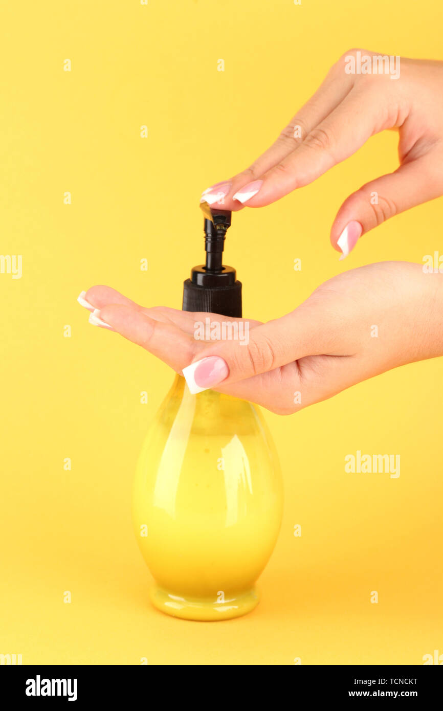 woman squeezing lotion on her hand, on yellow background close-up Stock ...