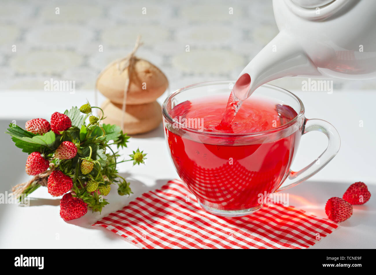 Cup of hot berry tea is poured from a teapot into a glass Cup, cookies ...