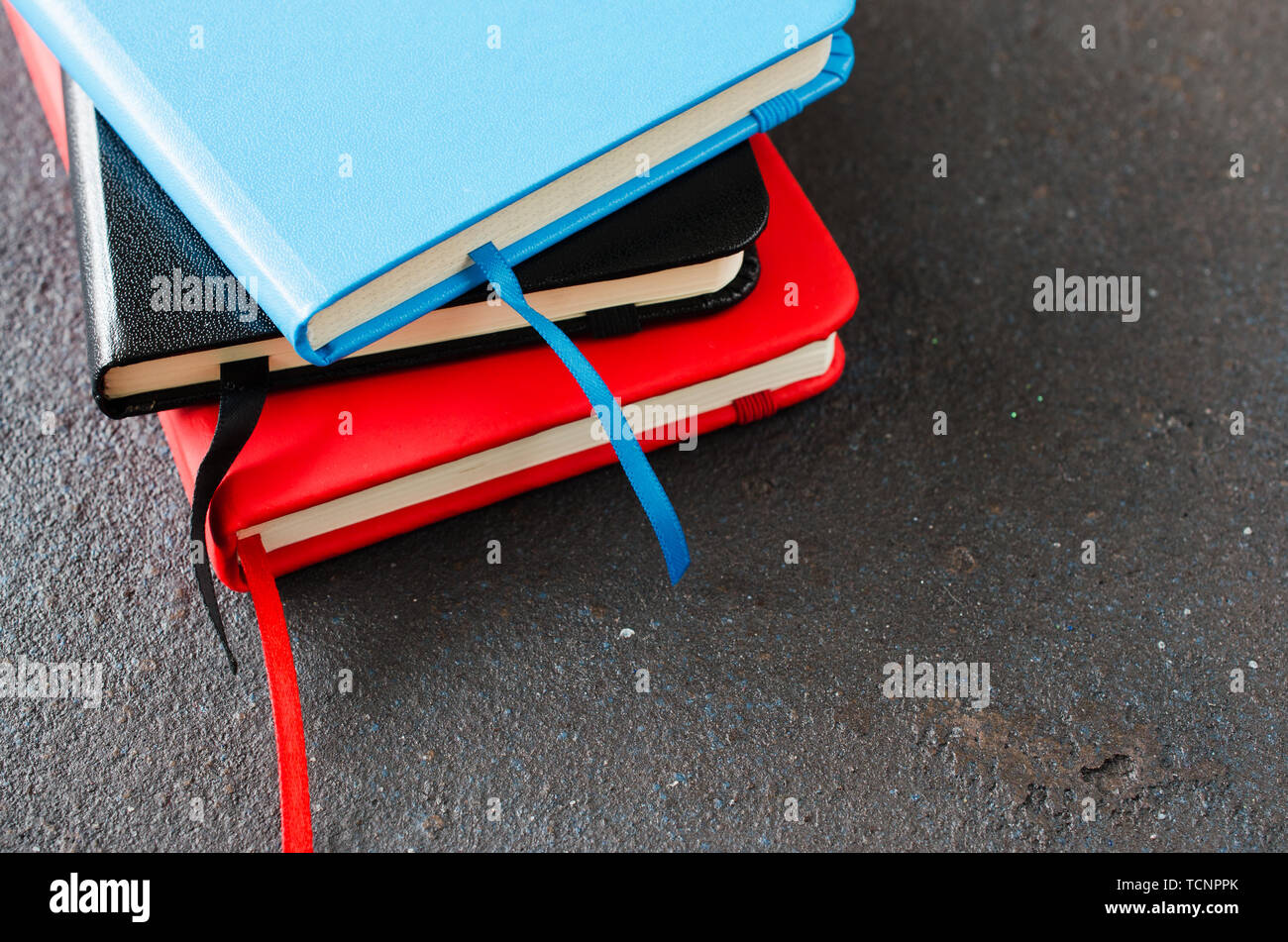 Stack of colorful notebooks for writing or books on dark background ...