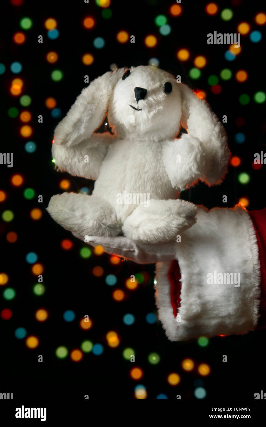 Santa Claus hand holding toy rabbit on bright background Stock Photo ...
