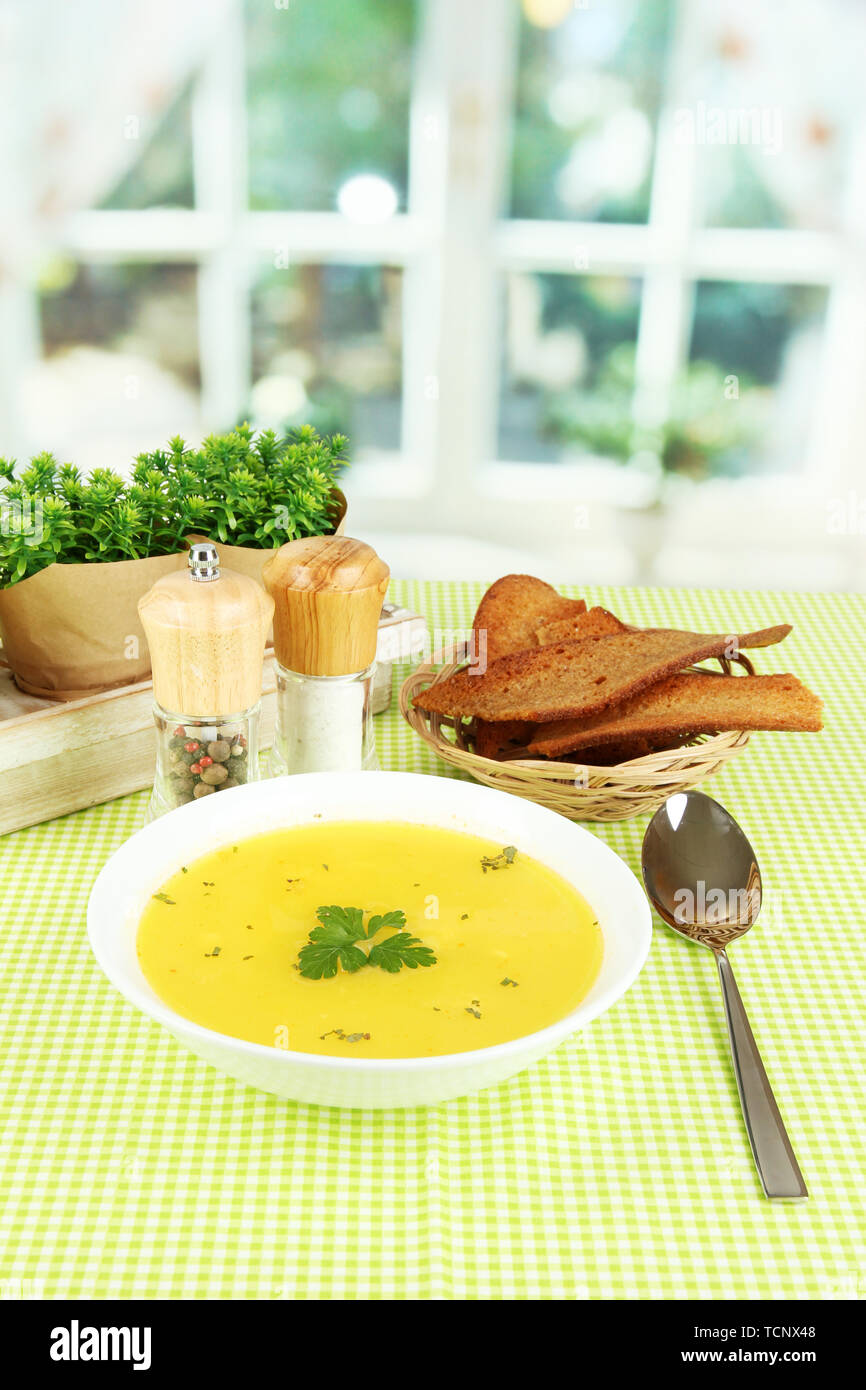 Fragrant soup in white plate on green tablecloth on window background ...