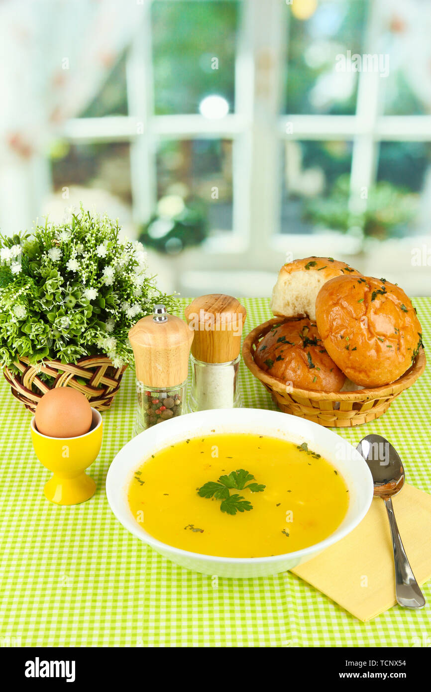Fragrant soup in white plate on green tablecloth on window background ...