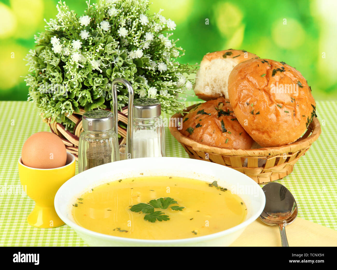 Fragrant soup in white plate on green tablecloth on natural background ...