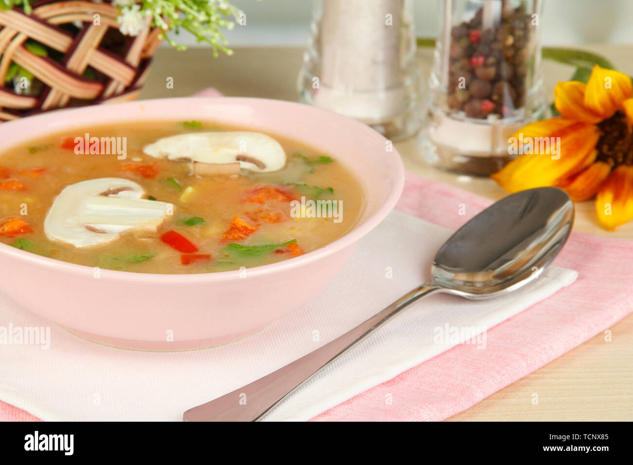 Fragrant soup in pink plate on table on window background close-up ...