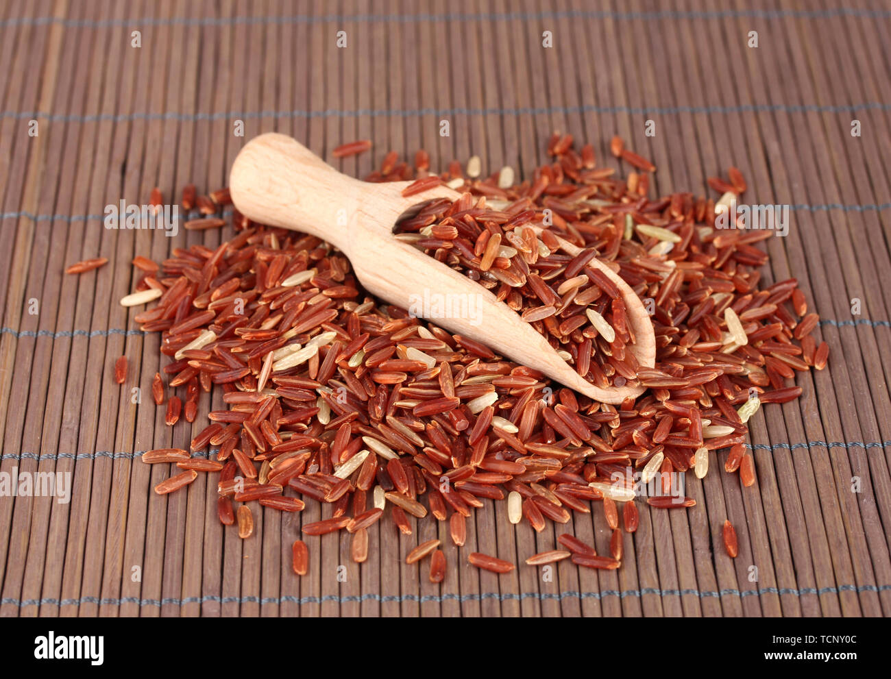 red rice in wooden scoop on bamboo mat Stock Photo - Alamy