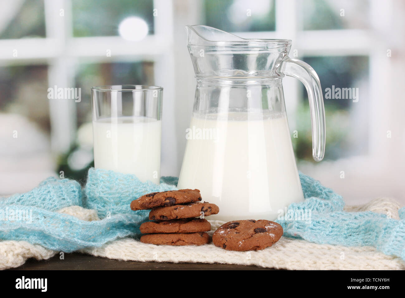 Pitcher and glass of milk with cookies on crewnecks knitwear on wooden ...