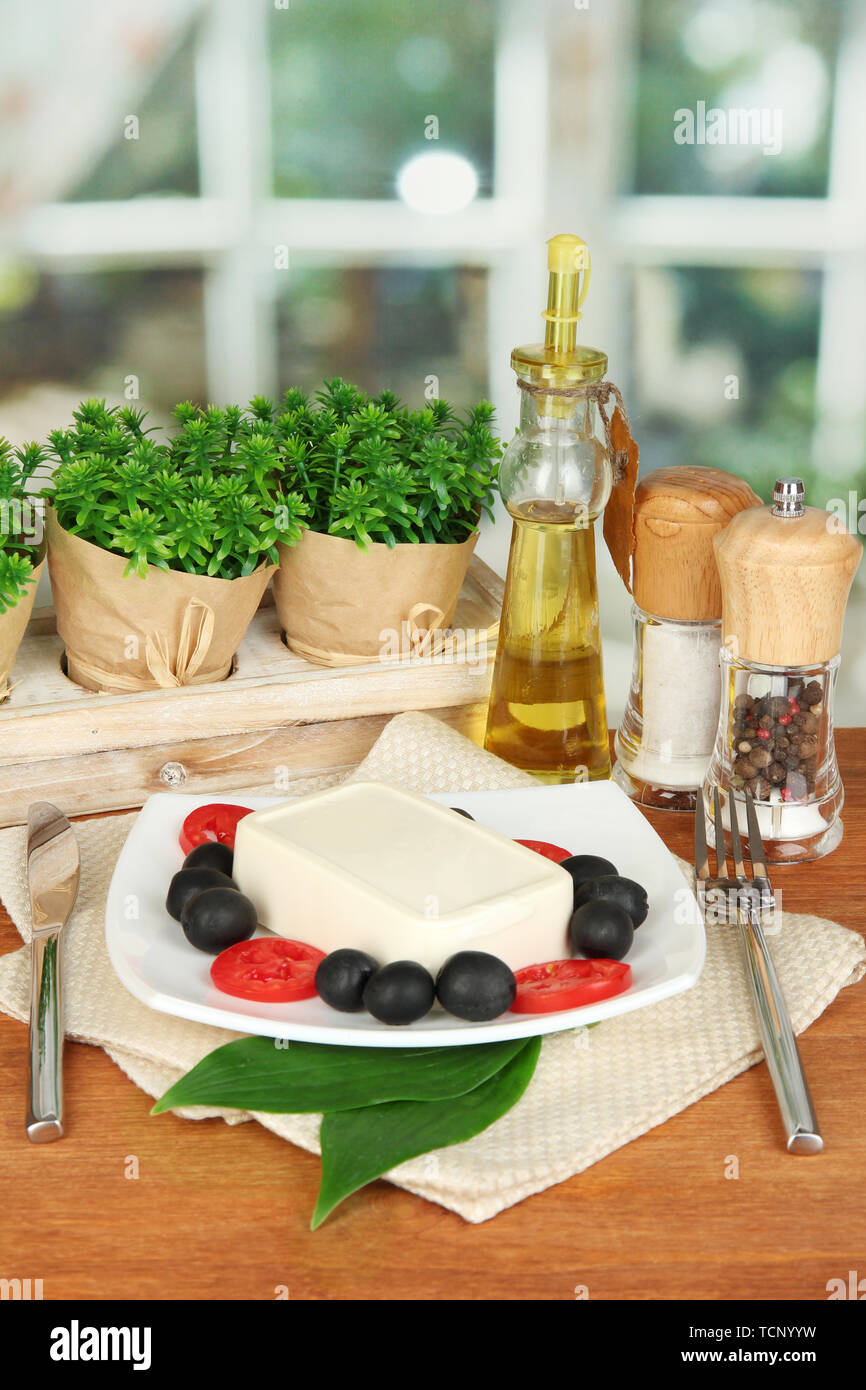 Feta cheese on plate decorated with spices and oil on wooden table on ...