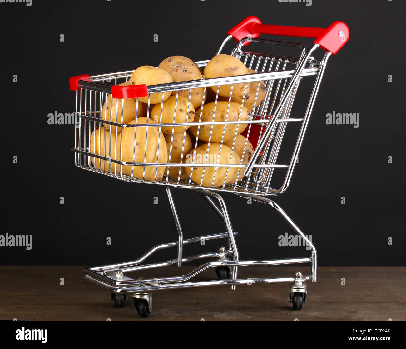 Ripe potatoes in trolley on wooden table on black background Stock ...