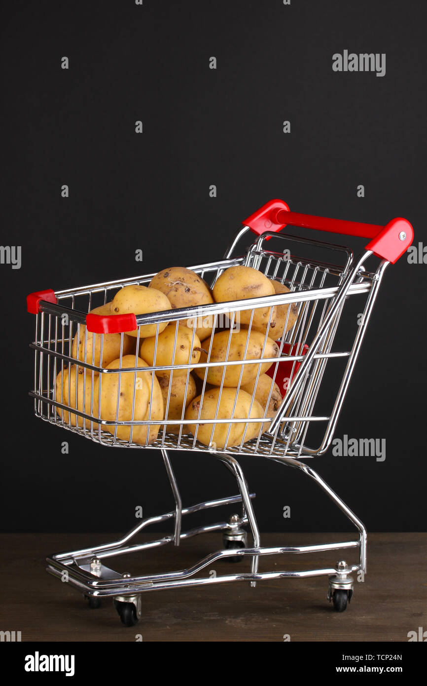Ripe potatoes in trolley on wooden table on black background Stock ...