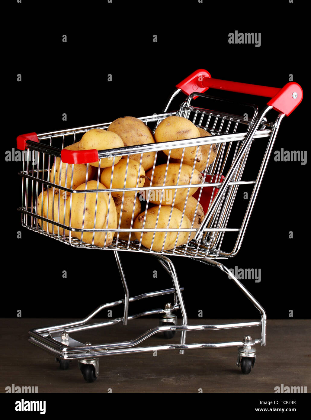Ripe potatoes in trolley on wooden table on black background Stock ...