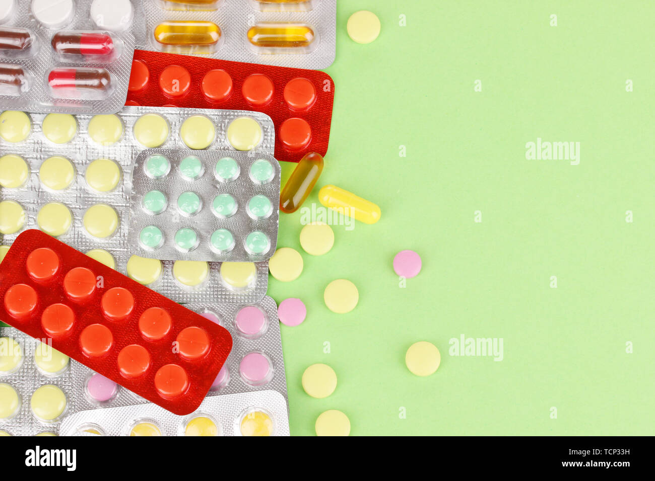 Capsules and pills packed in blisters on green background Stock Photo ...