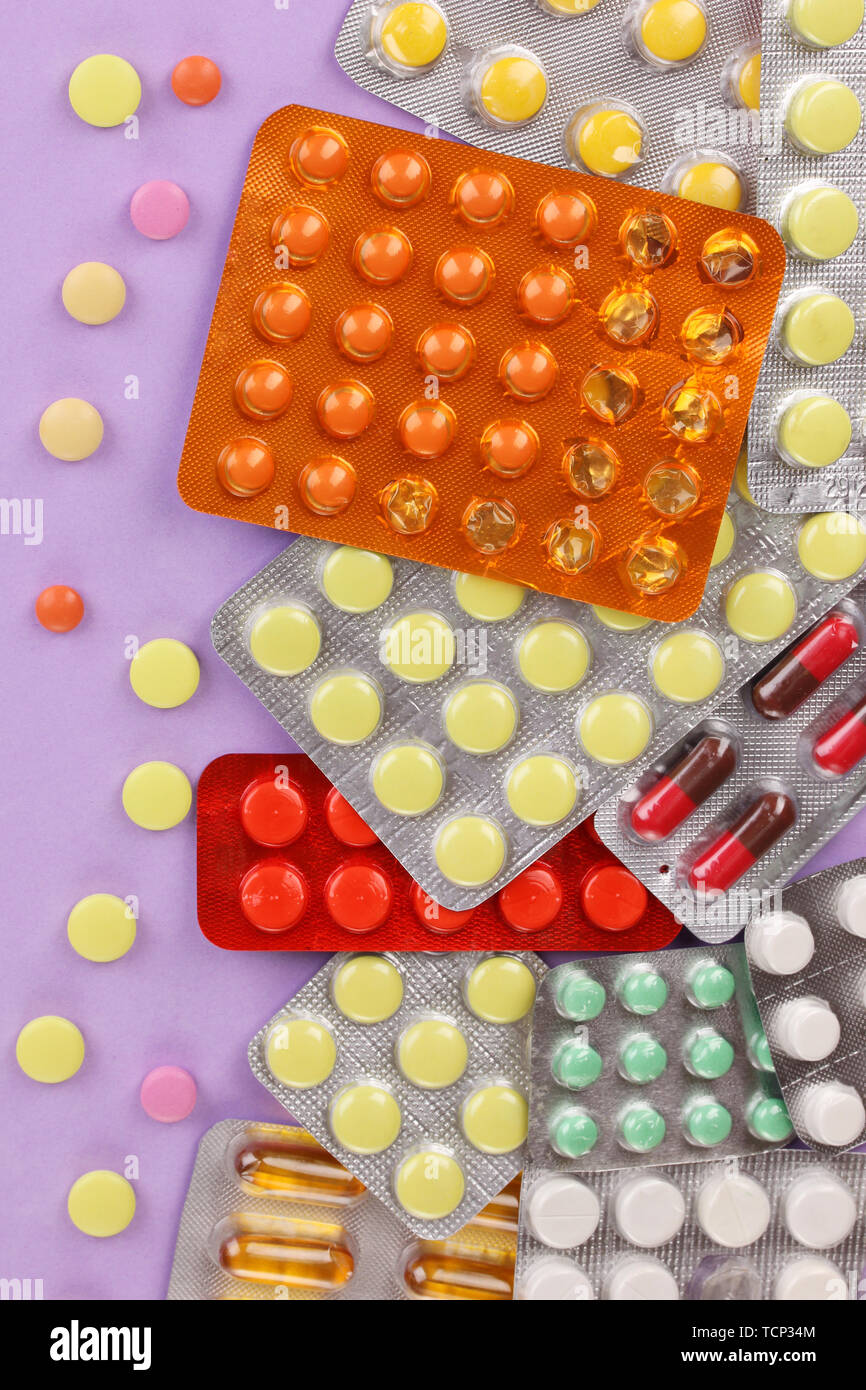 Capsules and pills packed in blisters on purple background Stock Photo ...