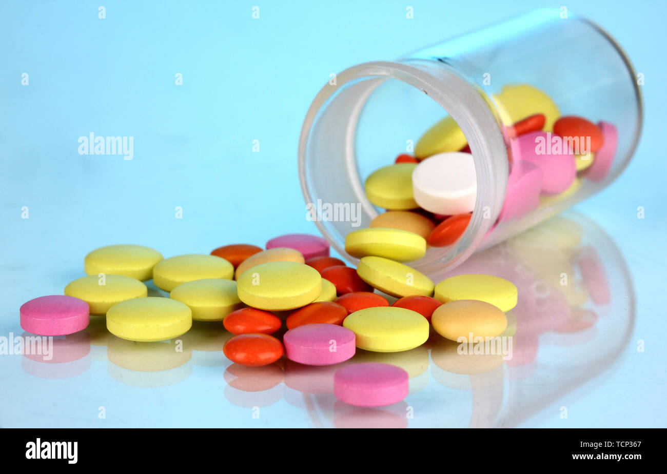 Pills in receptacle on blue background Stock Photo - Alamy