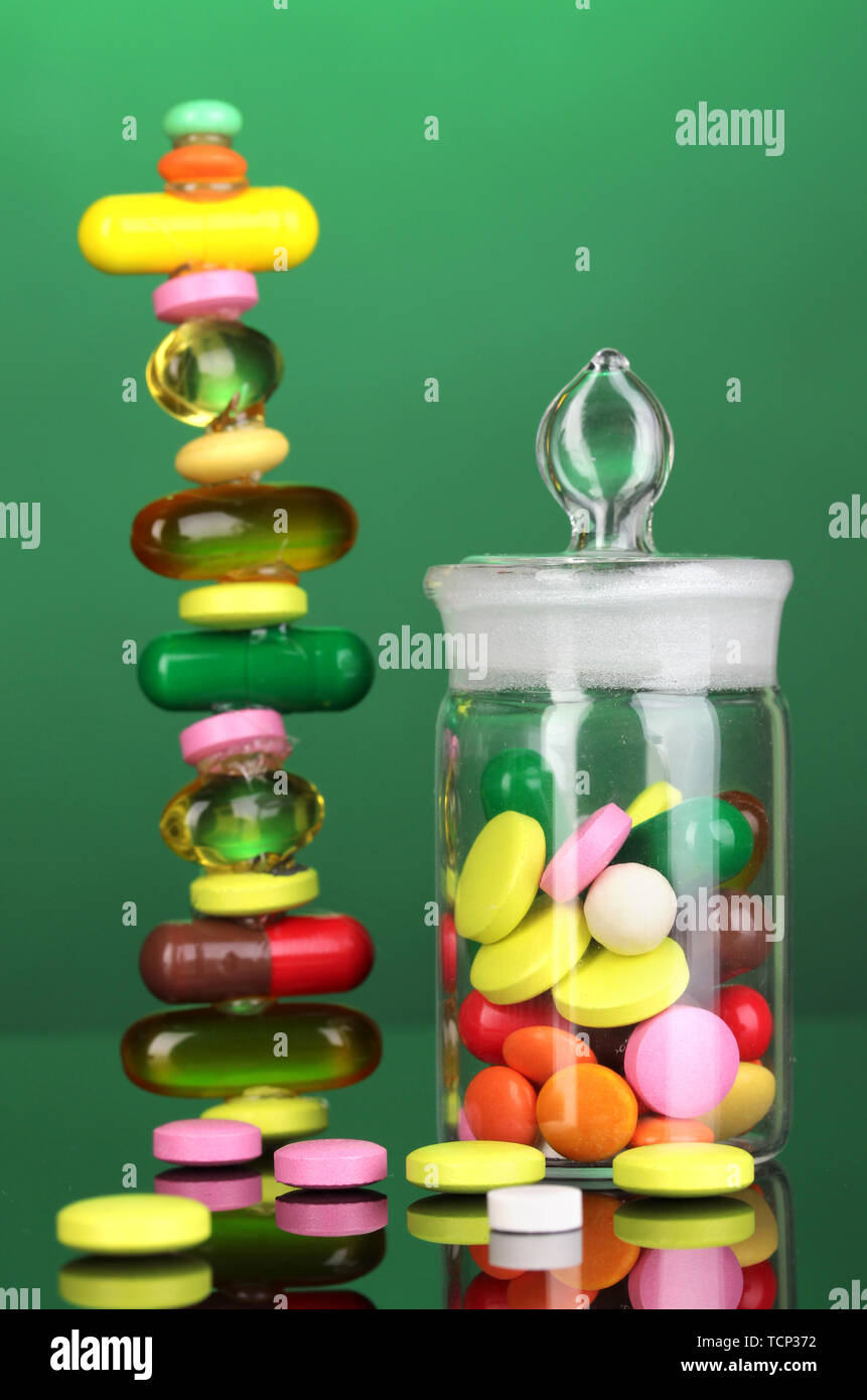 Capsules and pills hill and in receptacle on green background Stock ...