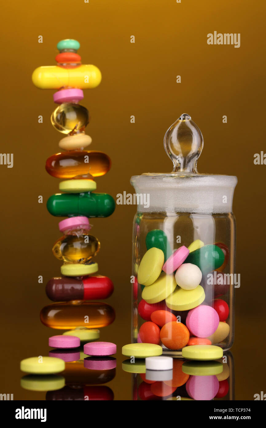Capsules and pills hill and in receptacle on yellow background Stock ...