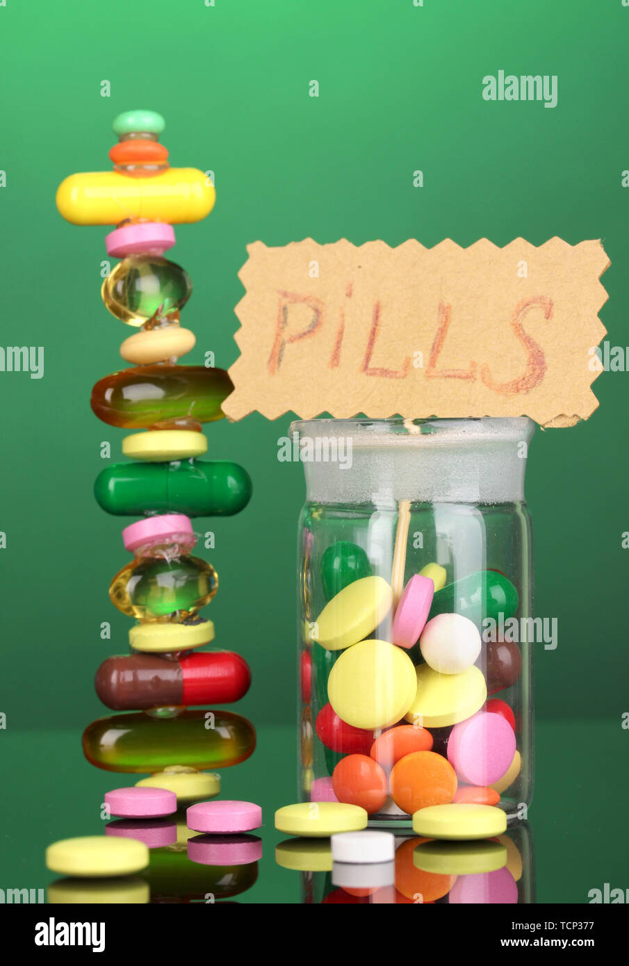 Capsules and pills hill and in receptacle on green background Stock ...