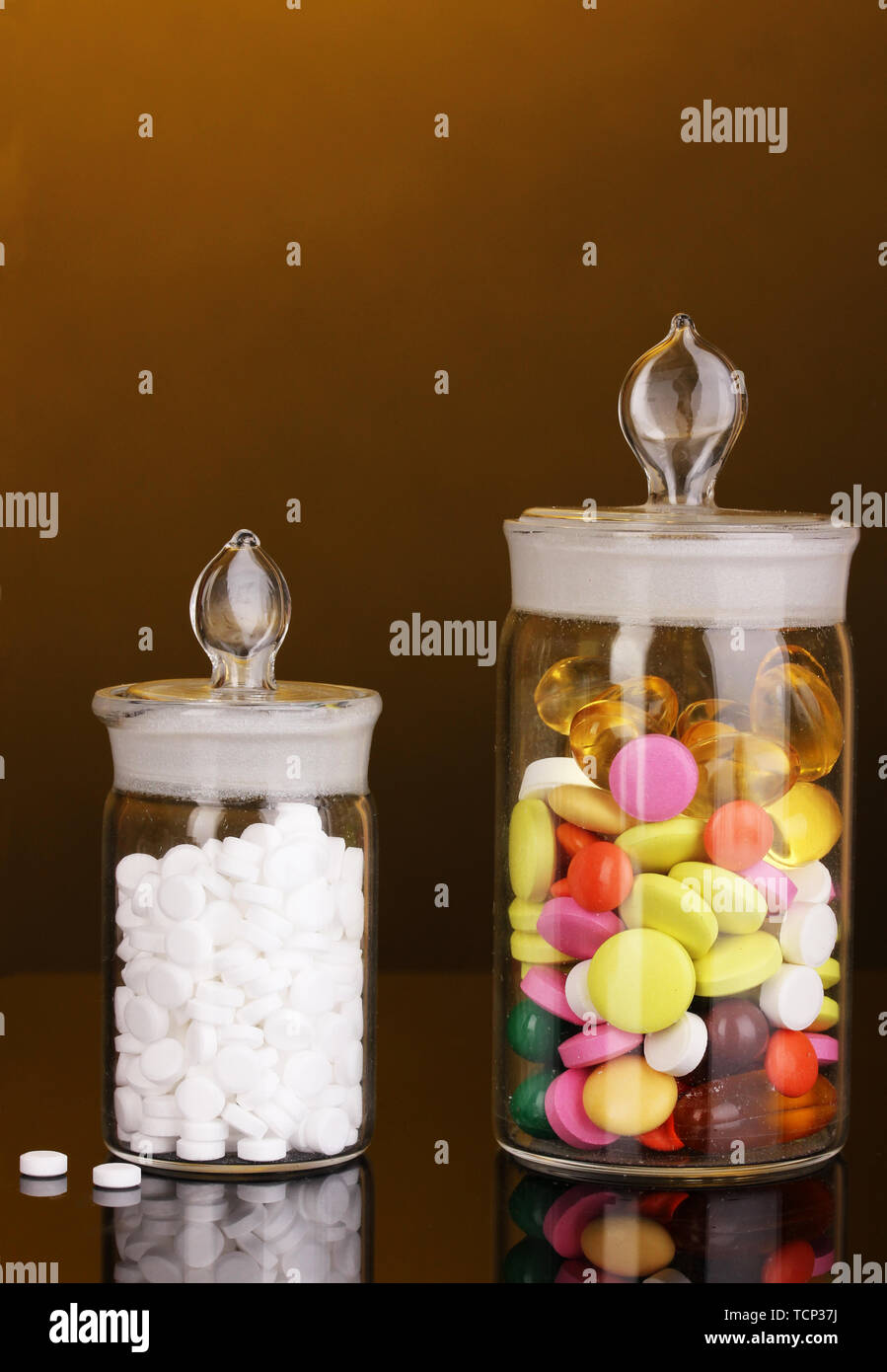 Capsules and pills in receptacles on orange background Stock Photo - Alamy