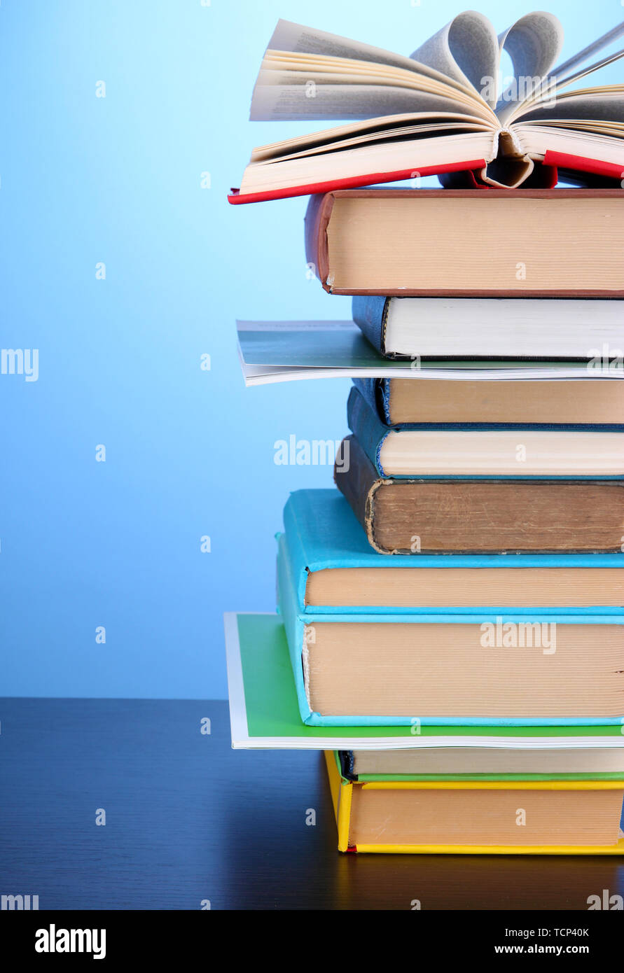 Stack of interesting books and magazines on wooden table on blue ...