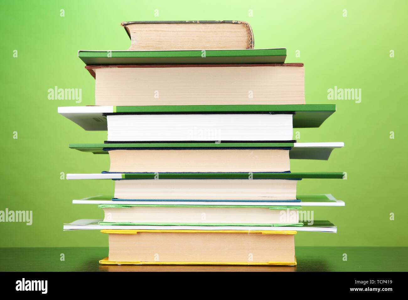 Stack of interesting books and magazines on wooden table on green ...