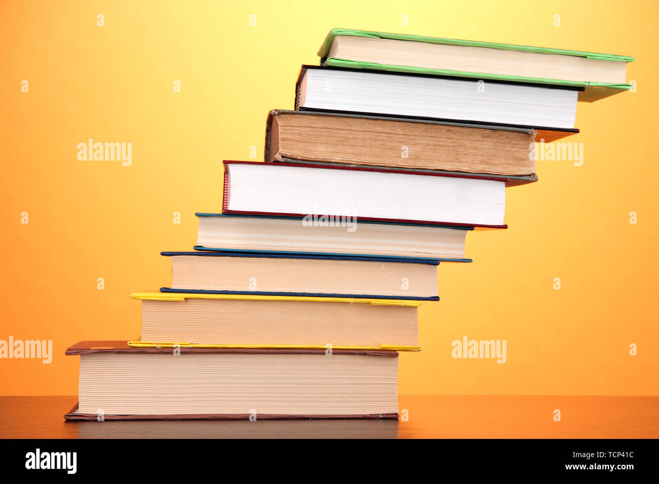Stack of interesting books and magazines on wooden table on orange ...