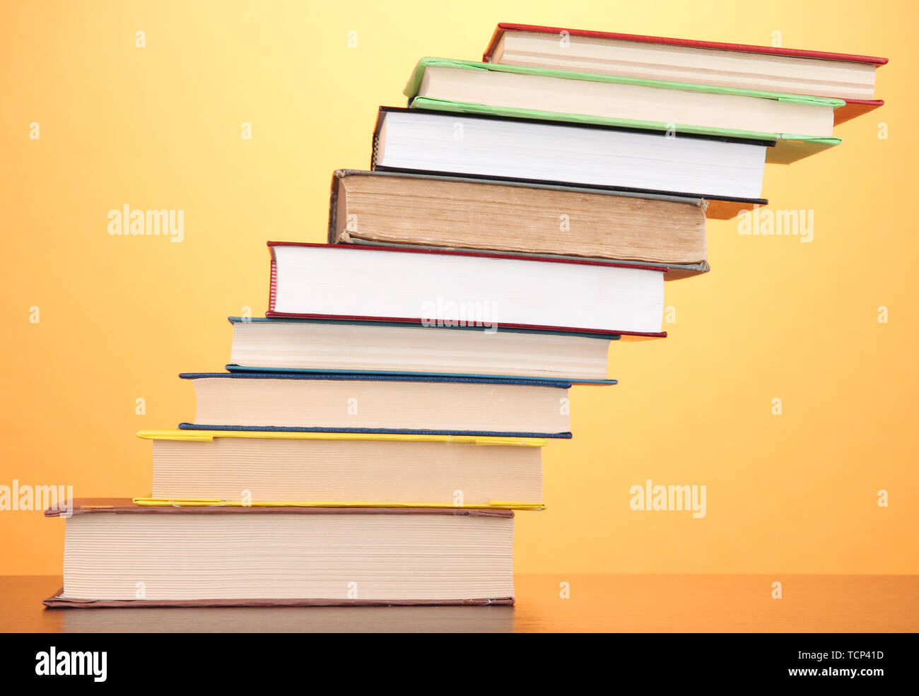 Stack of interesting books and magazines on wooden table on orange ...