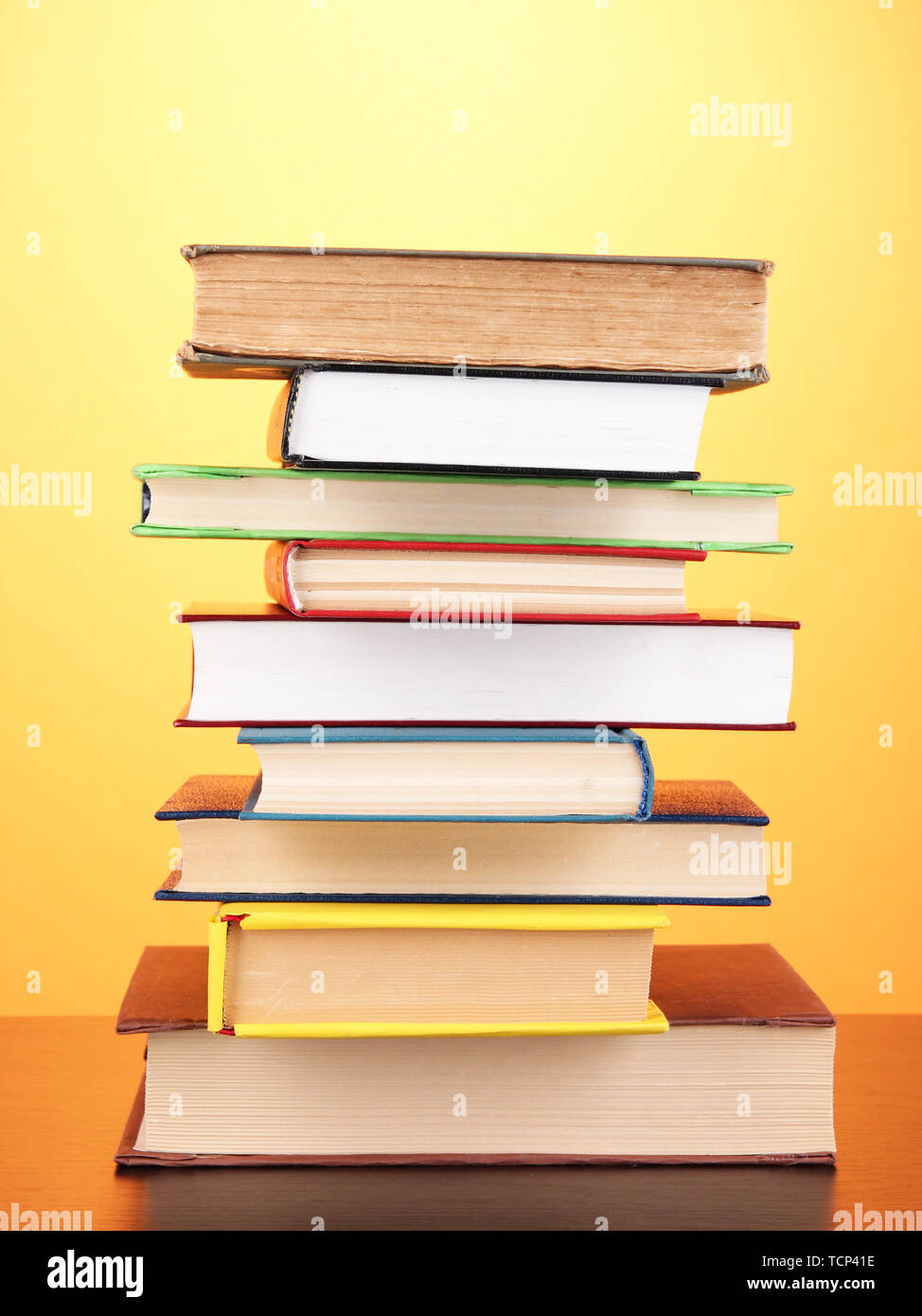 Stack of interesting books and magazines on wooden table on orange ...