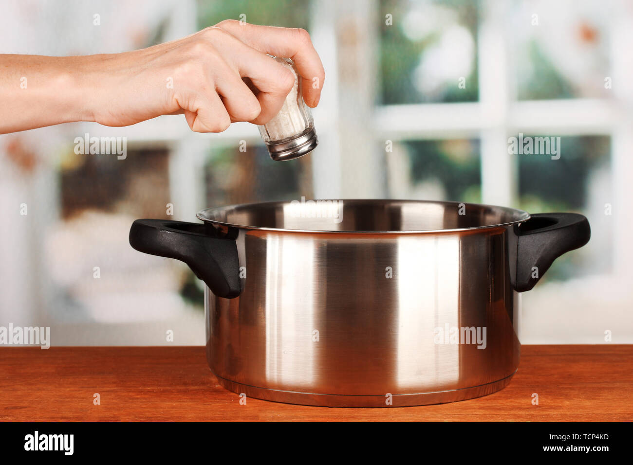 Hand adding salt using salt shaker on bright background Stock Photo - Alamy