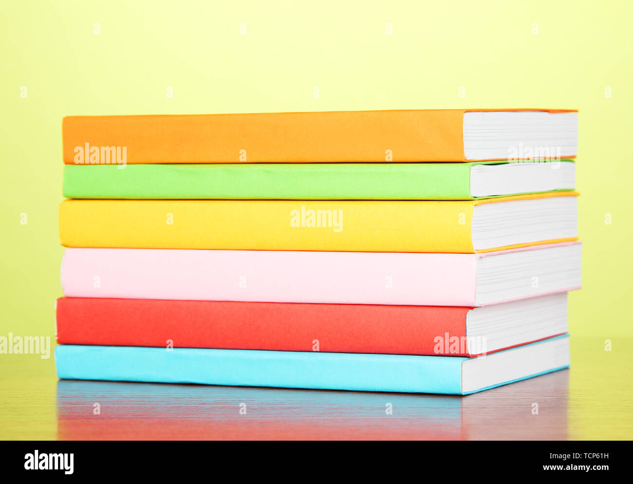 Stack of multicolor books on green background Stock Photo - Alamy