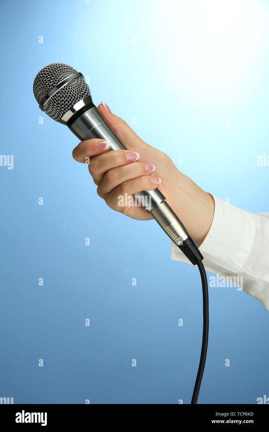 female hand with microphone, on blue background Stock Photo - Alamy