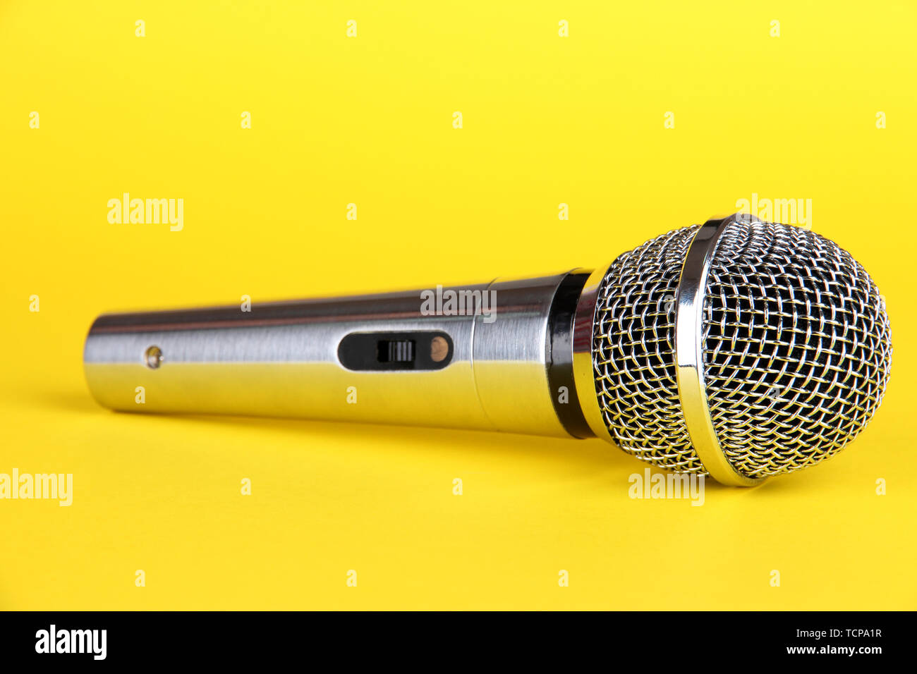 Silver microphone on yellow background Stock Photo - Alamy