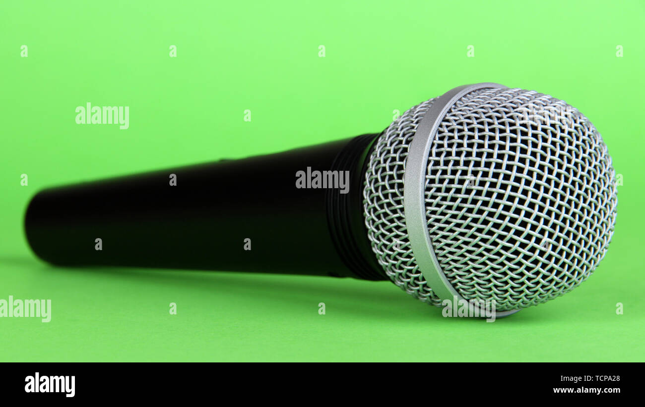 Black microphone on green background Stock Photo - Alamy