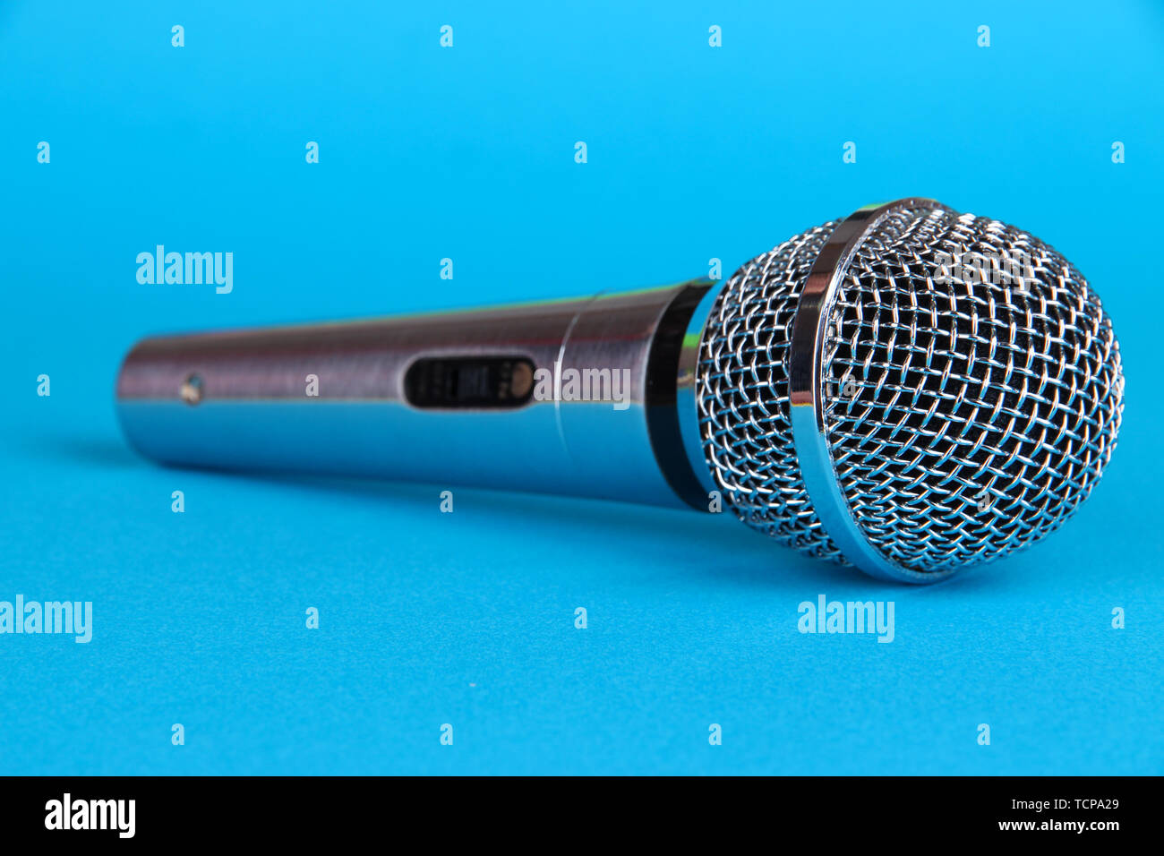 Silver microphone on blue background Stock Photo - Alamy