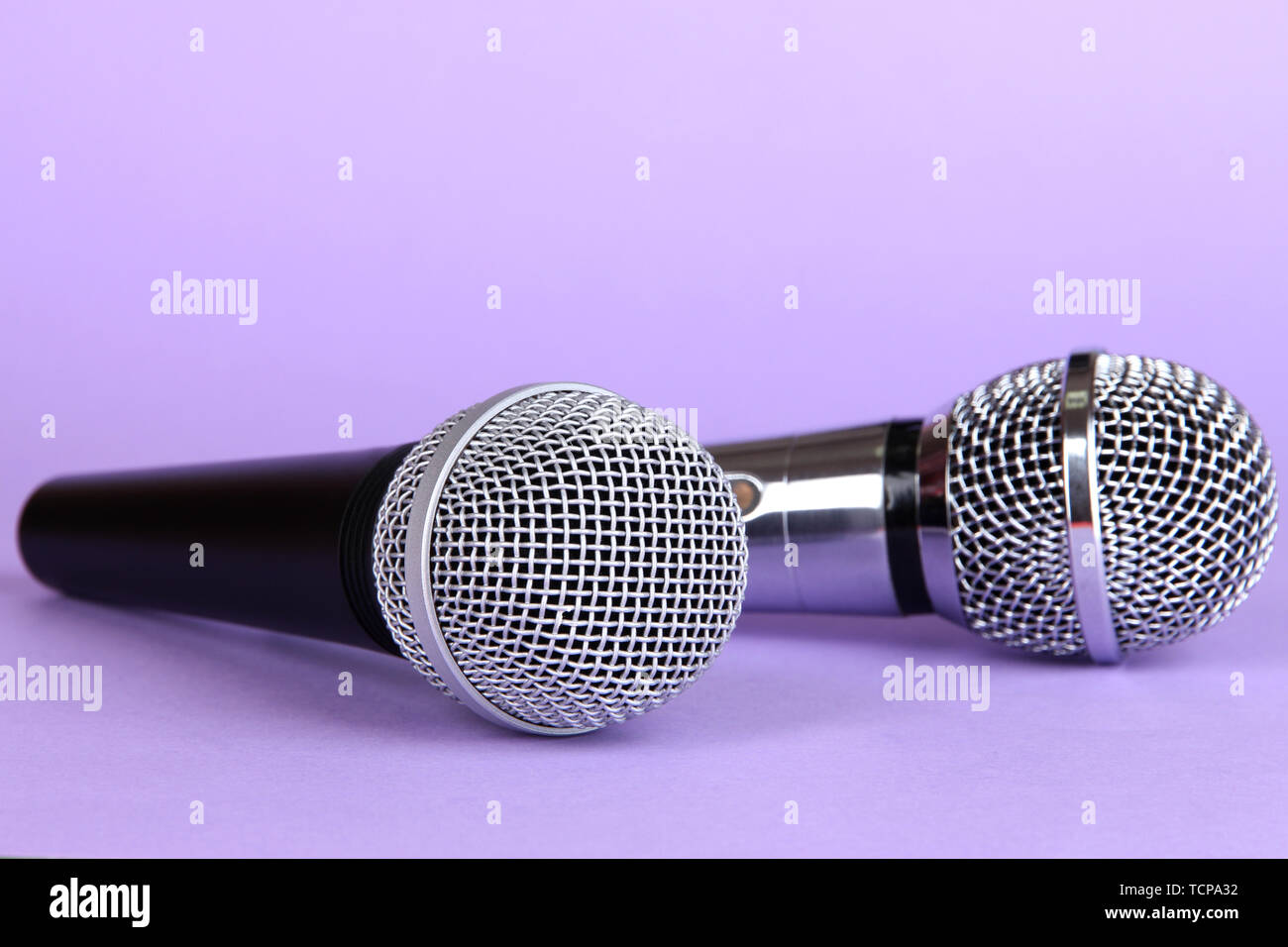 Silver and black microphones on purple background Stock Photo - Alamy