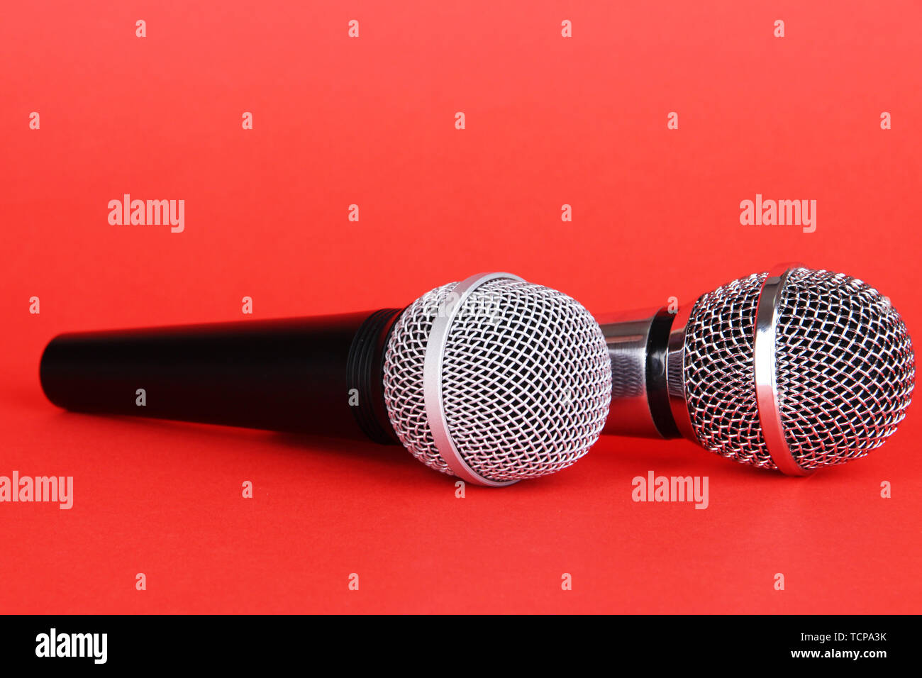 Silver and black microphones on red background Stock Photo - Alamy