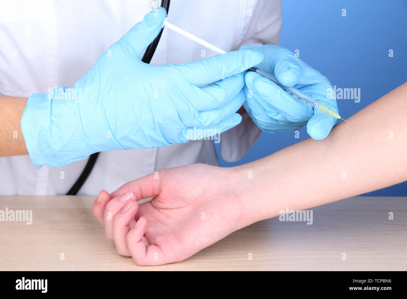 vaccine injection in hand on blue background Stock Photo - Alamy