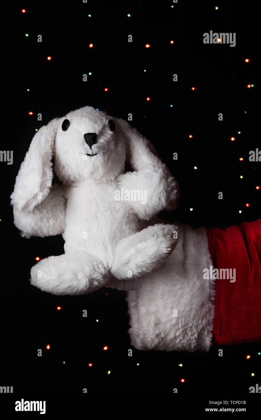 Santa Claus hand holding toy rabbit on bright background Stock Photo ...