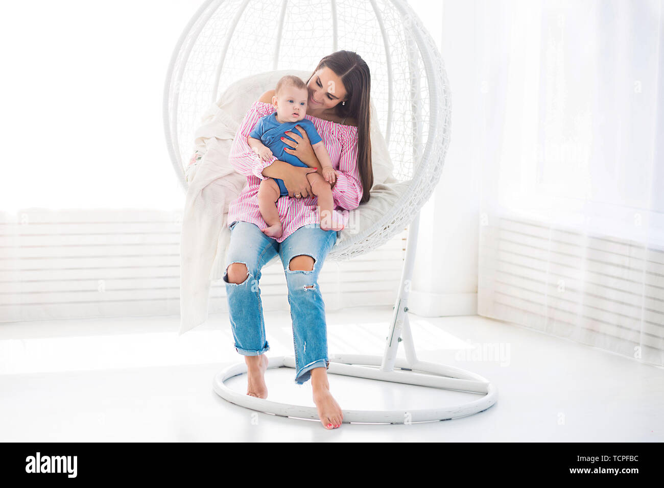 photo of mom and son are sitting in a beautiful white round chair Stock ...