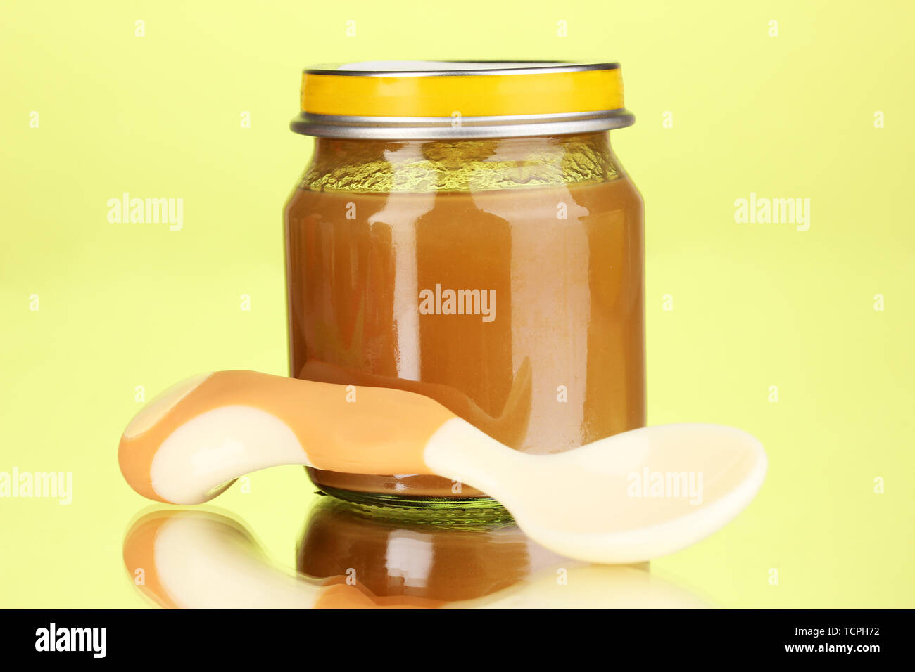 Useful and tasty baby food with beige small spoon on green background ...