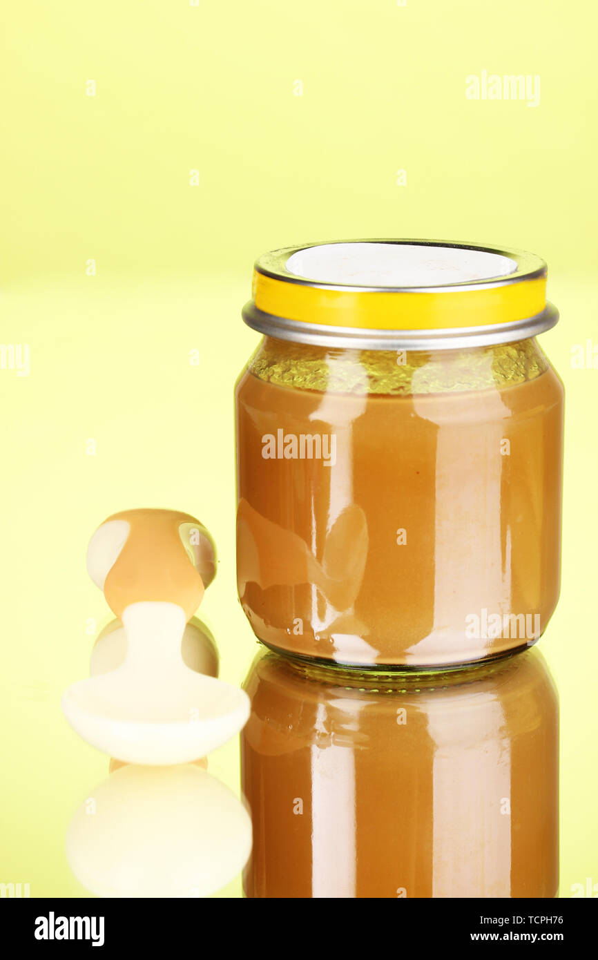 Useful and tasty baby food with beige small spoon on green background ...