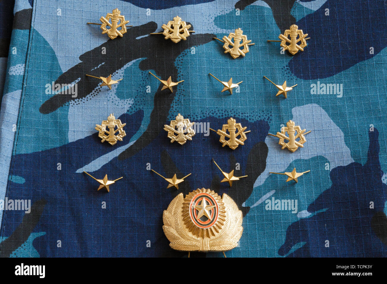 Gold stars and emblems on blue camouflage fabric. Military emblems of ...