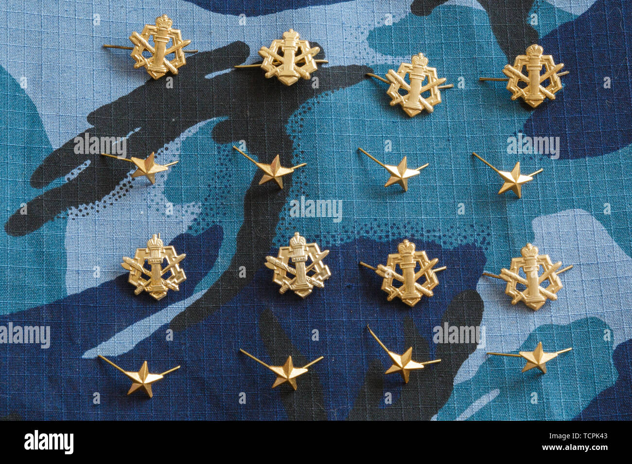 Gold stars and emblems on blue camouflage fabric. Military emblems of ...