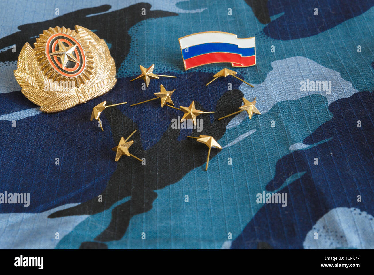 Gold stars and emblems on blue camouflage fabric. Military emblems of ...